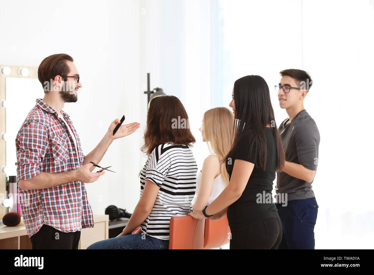 Professional hairdresser teaching trainees in salon. Apprenticeship ...