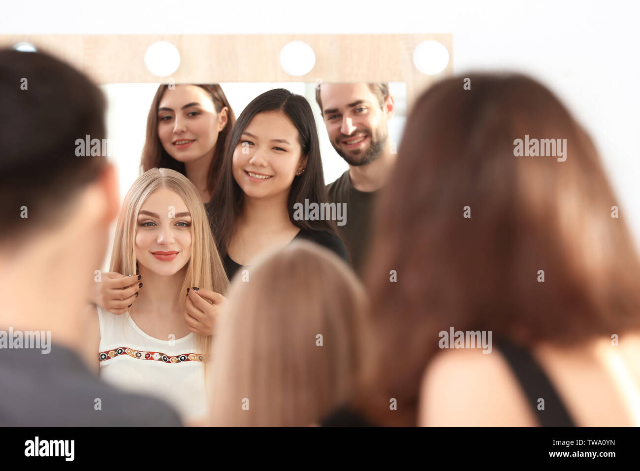 Professional hairdresser and trainees working with client in salon ...