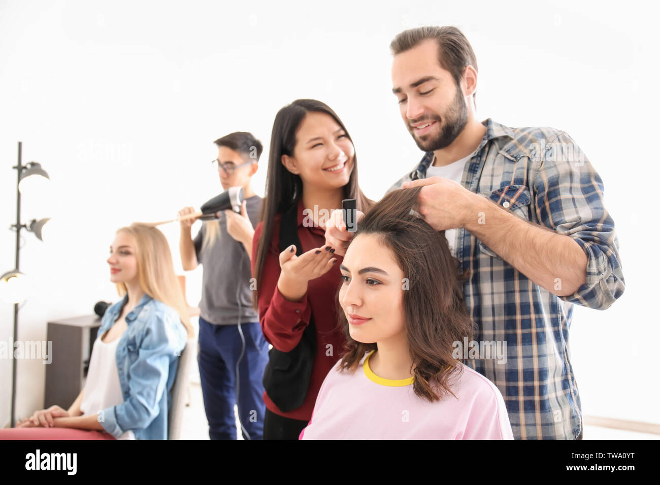 Professional hairdresser and trainees working with clients in salon ...