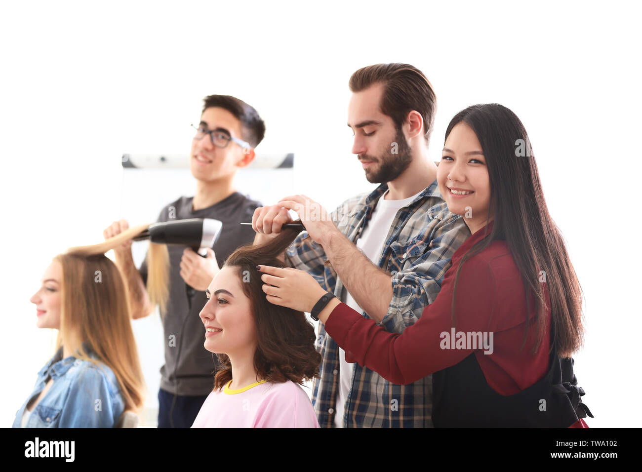 Professional hairdresser and trainees working with clients in salon ...