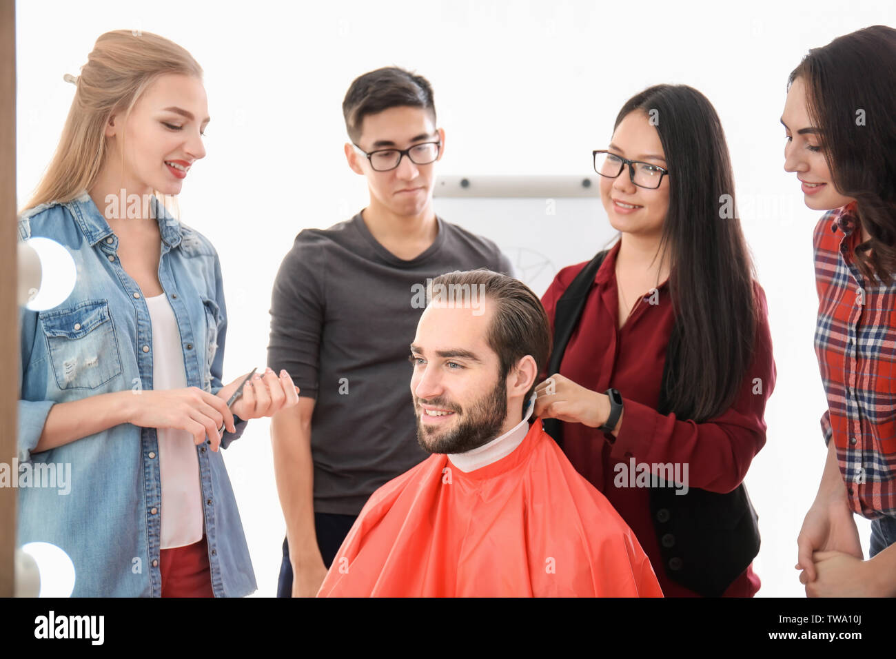Professional hairdresser and trainees working with client in salon ...