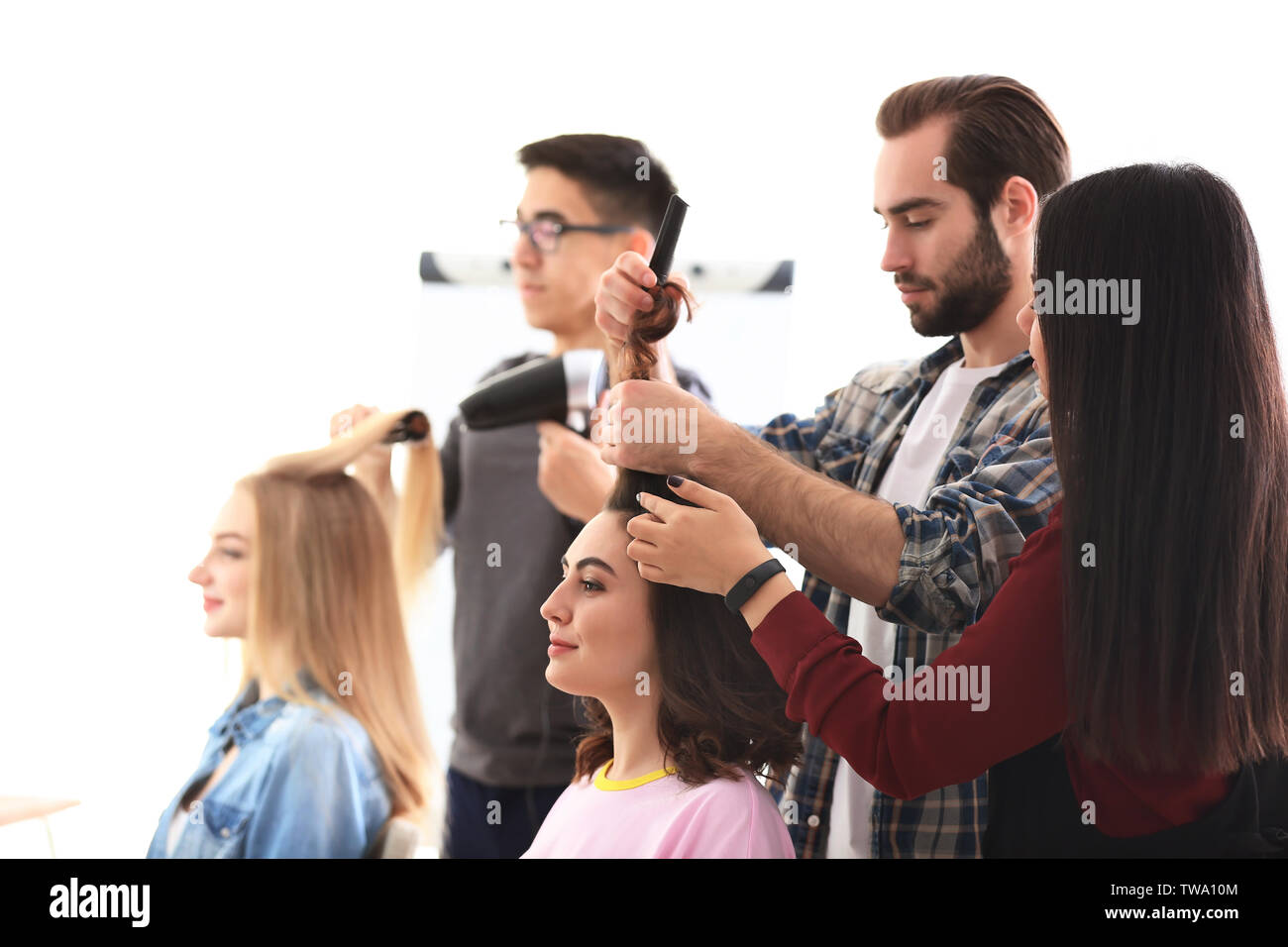 Professional hairdresser and trainees working with clients in salon ...