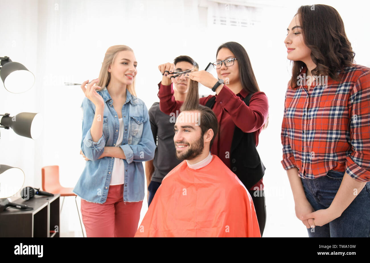 Professional hairdresser and trainees working with client in salon ...
