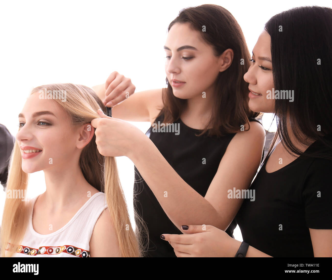 Professional hairdresser and trainees working with client in salon ...