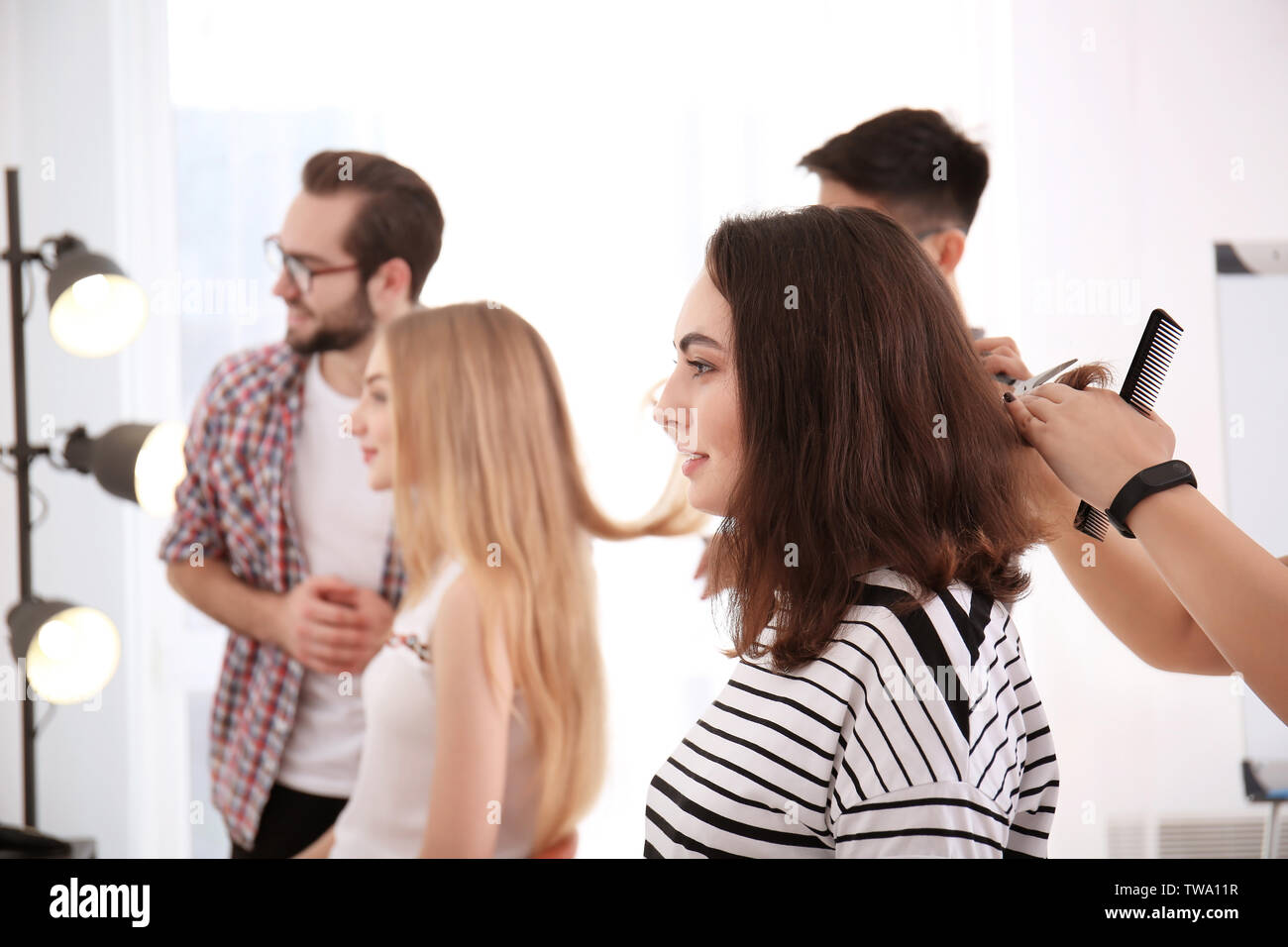 Professional hairdresser and trainees working with clients in salon ...