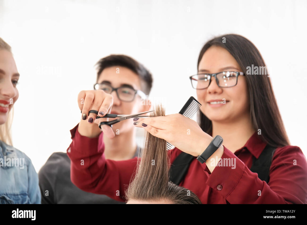 Professional hairdresser and trainees working with client in salon ...