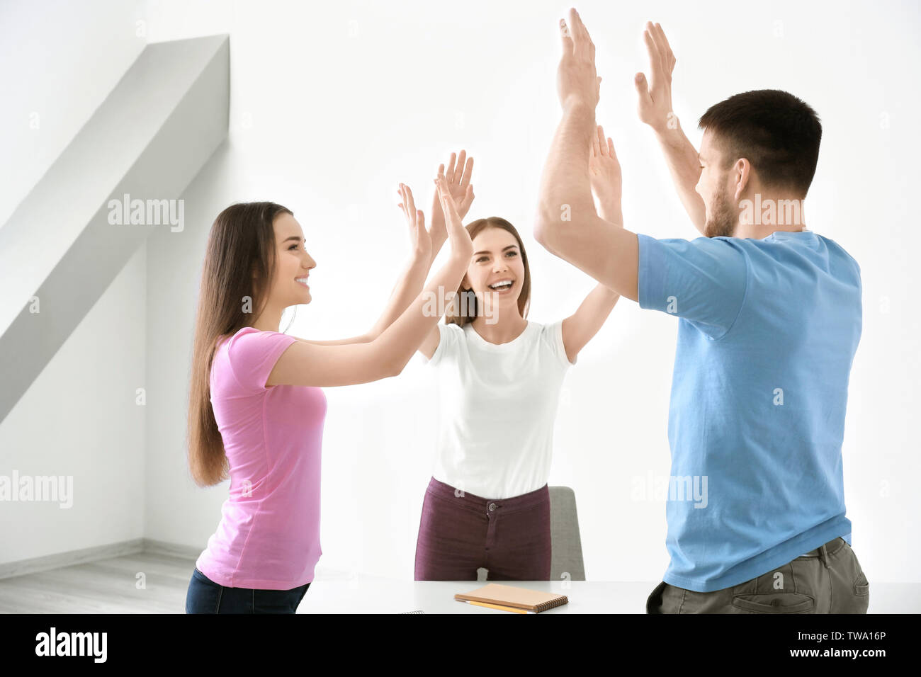 Young people giving high five to each other indoors. Unity concept ...
