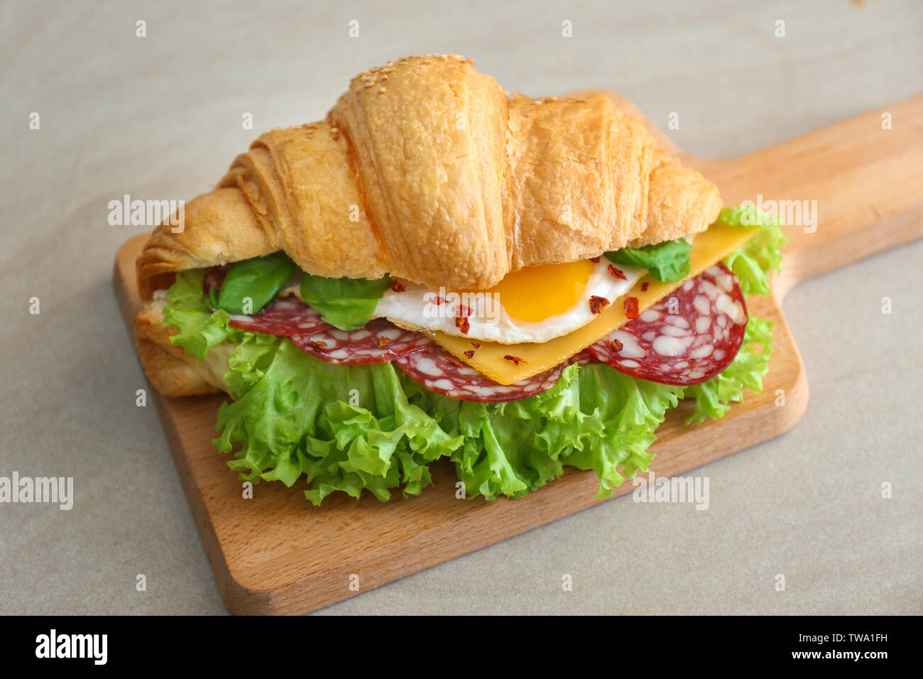 Wooden board with tasty croissant sandwich on table Stock Photo - Alamy