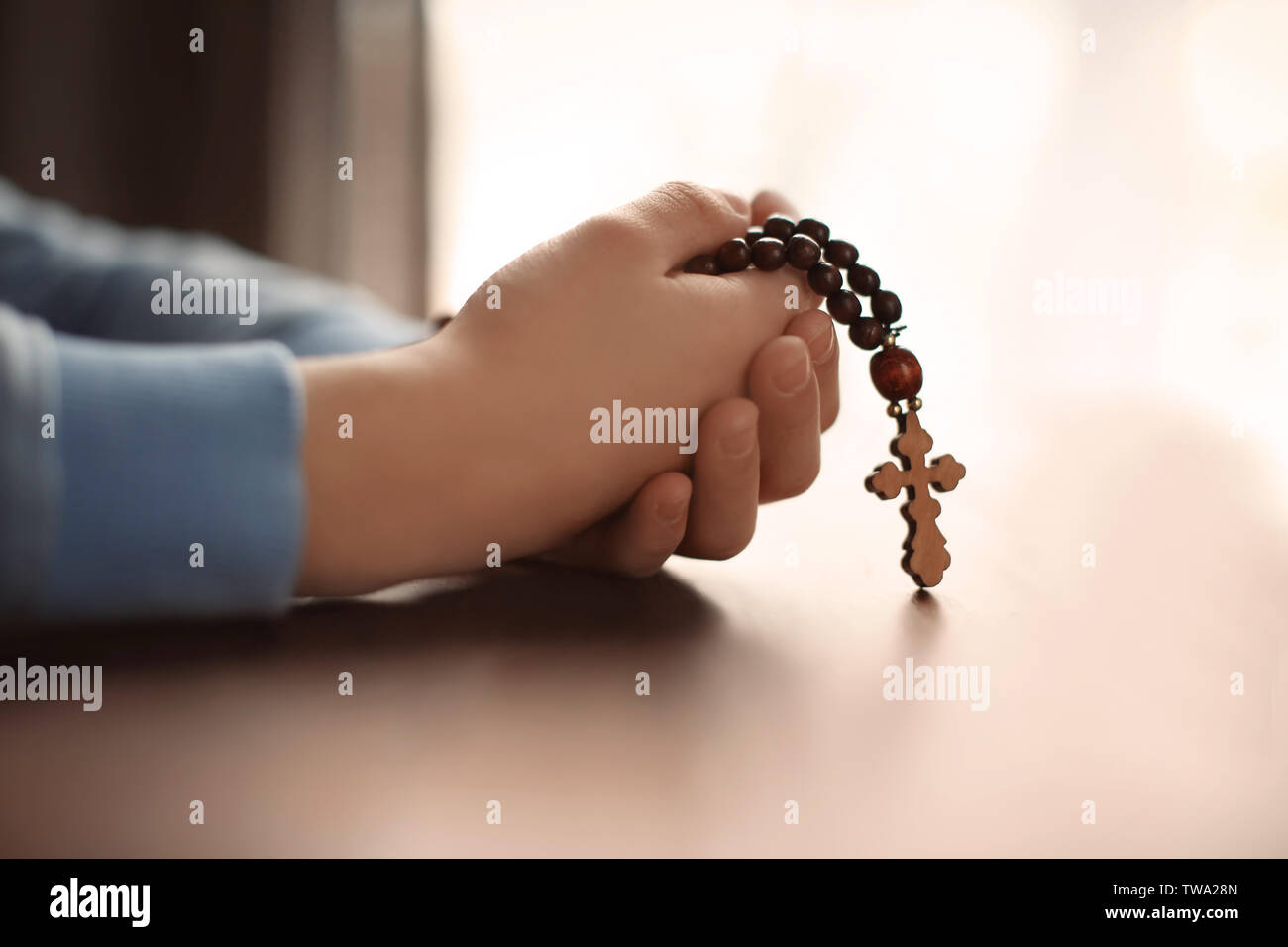 Little boy holding wooden cross at table Stock Photo - Alamy