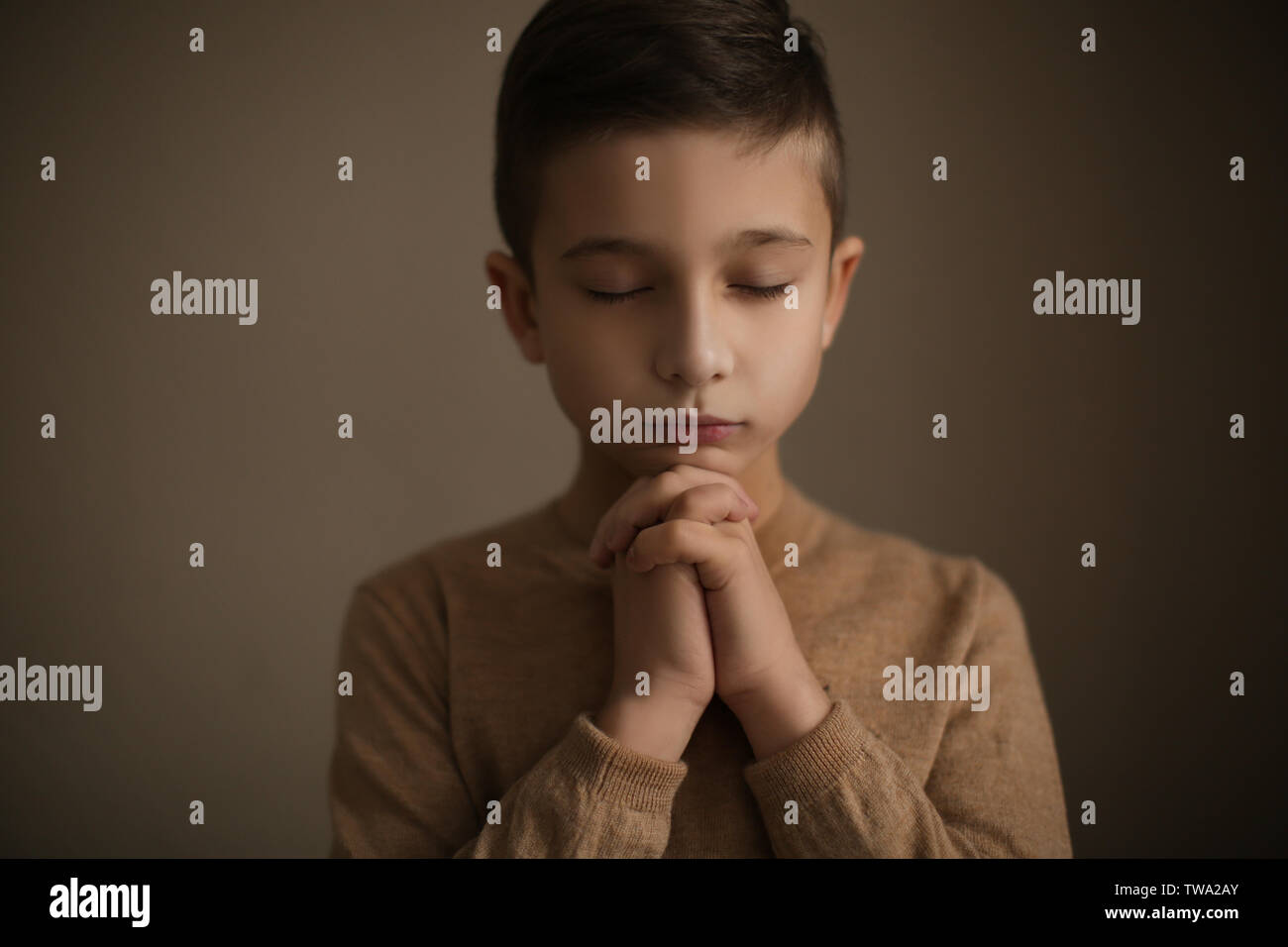 Little boy praying on dark background Stock Photo - Alamy