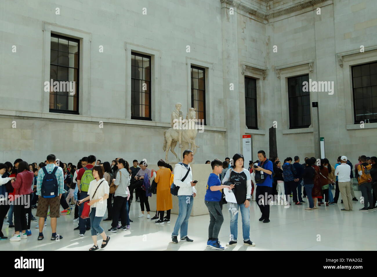 Group of Asian visitors stand around the marble Roman statue of a youth ...