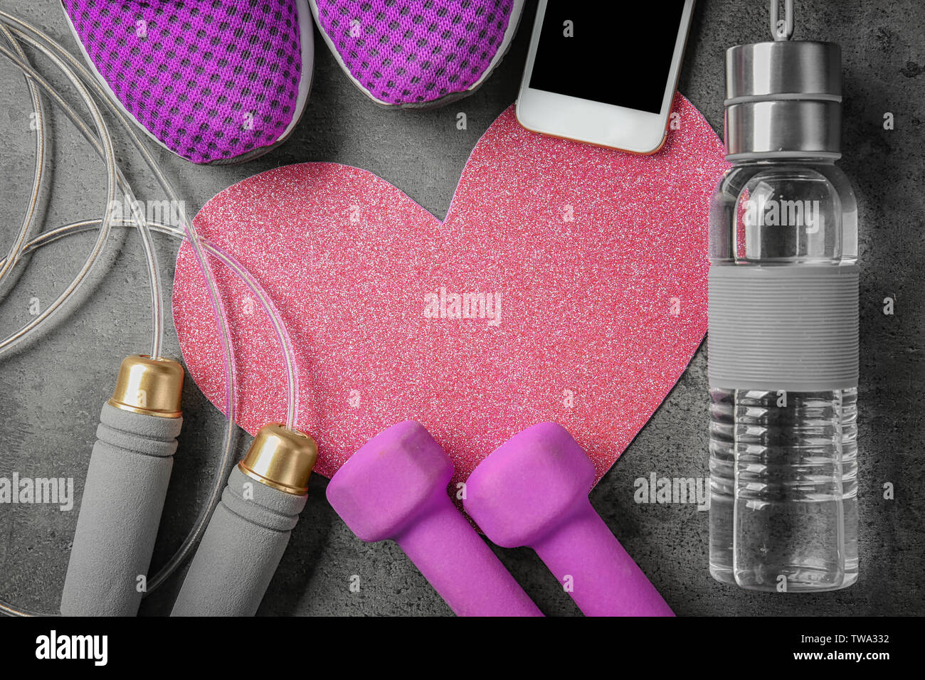 Gym stuff, phone and heart on grey background. Cardio training concept ...