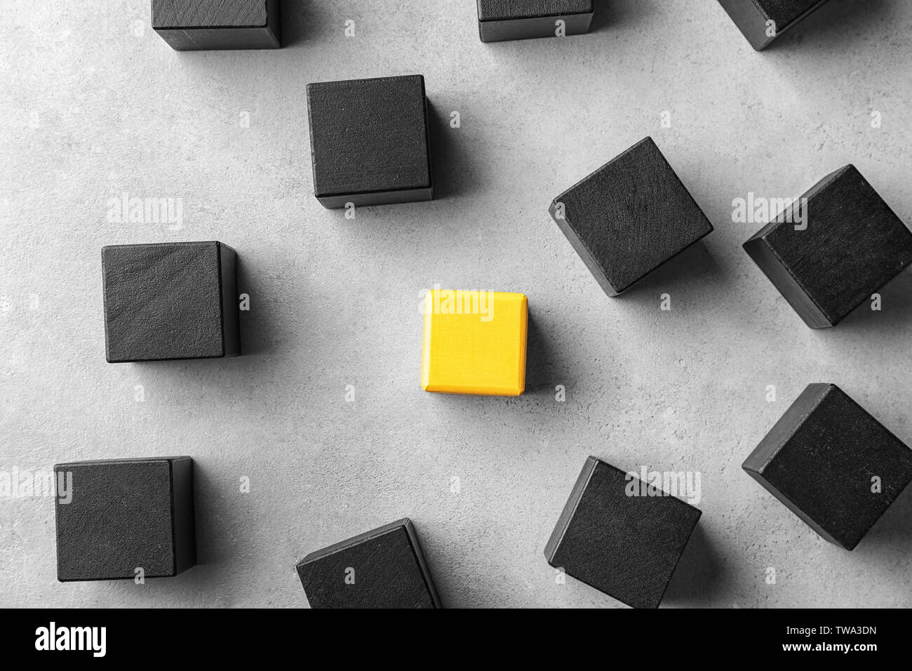 One yellow cube standing out from others on light background. Think ...