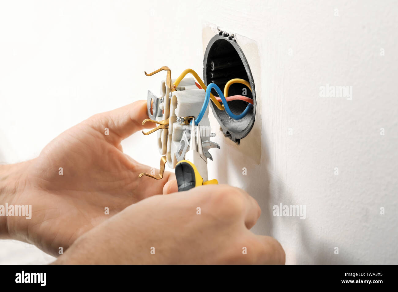 Electrician repairing socket on light wall Stock Photo - Alamy