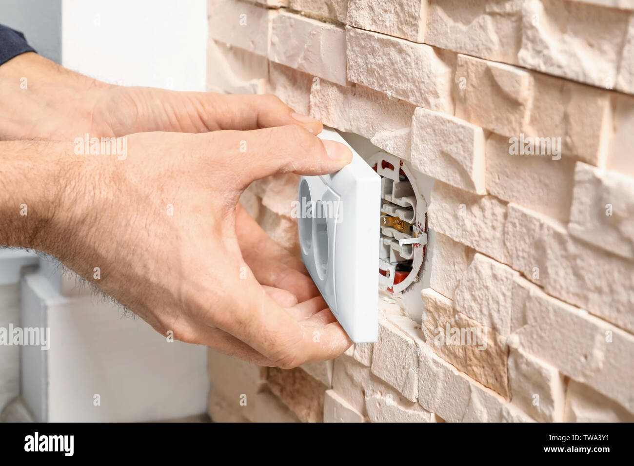 Electrician repairing socket on brick wall Stock Photo - Alamy