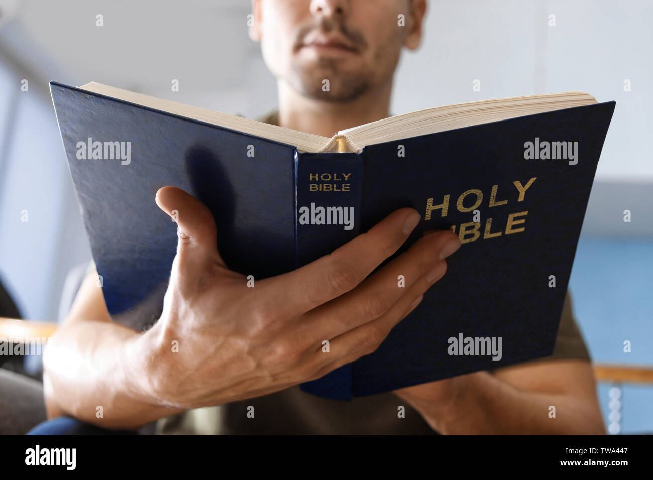 Religious young man reading Bible at home, closeup Stock Photo - Alamy