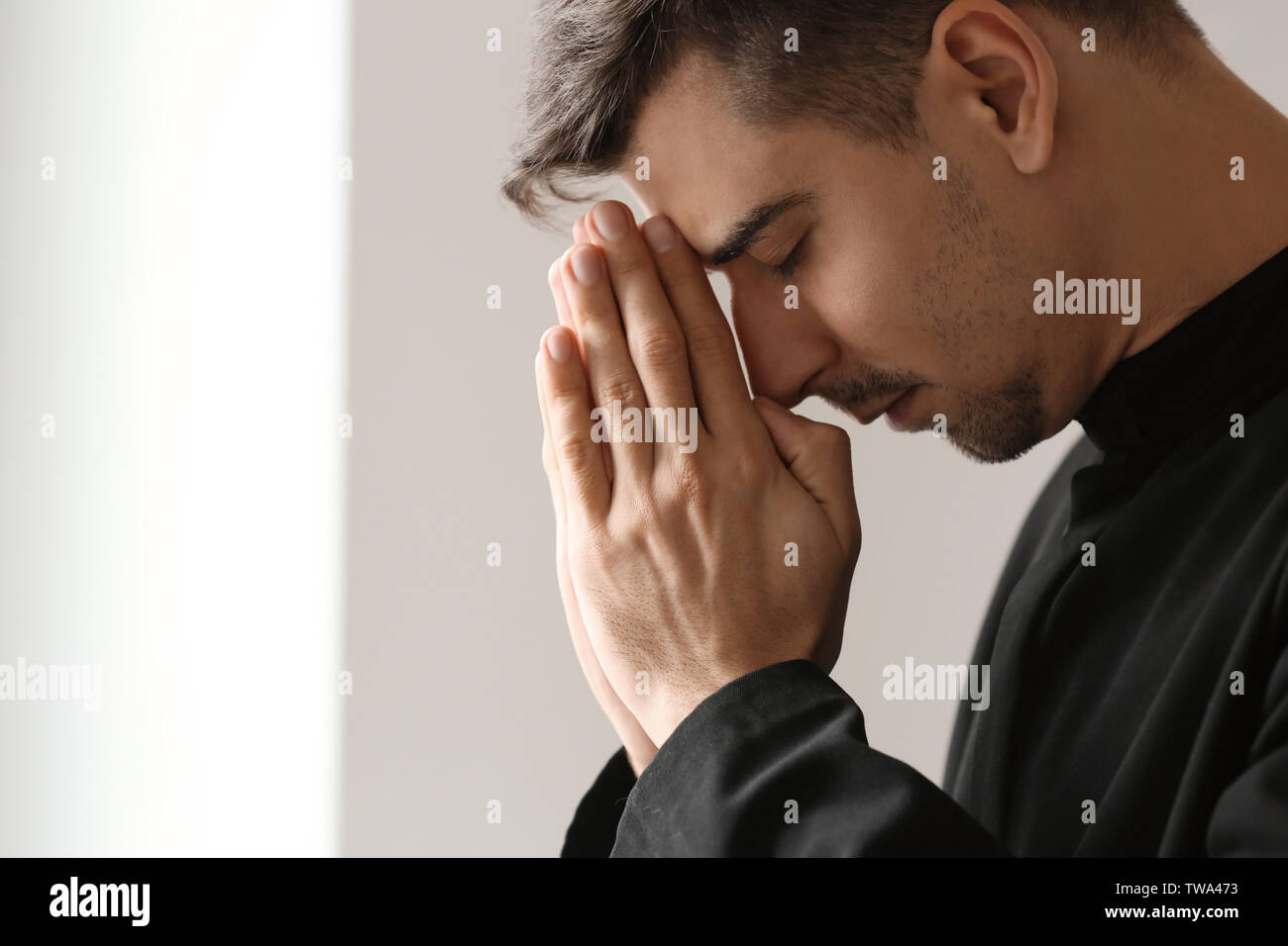 Young priest praying to God indoors Stock Photo - Alamy