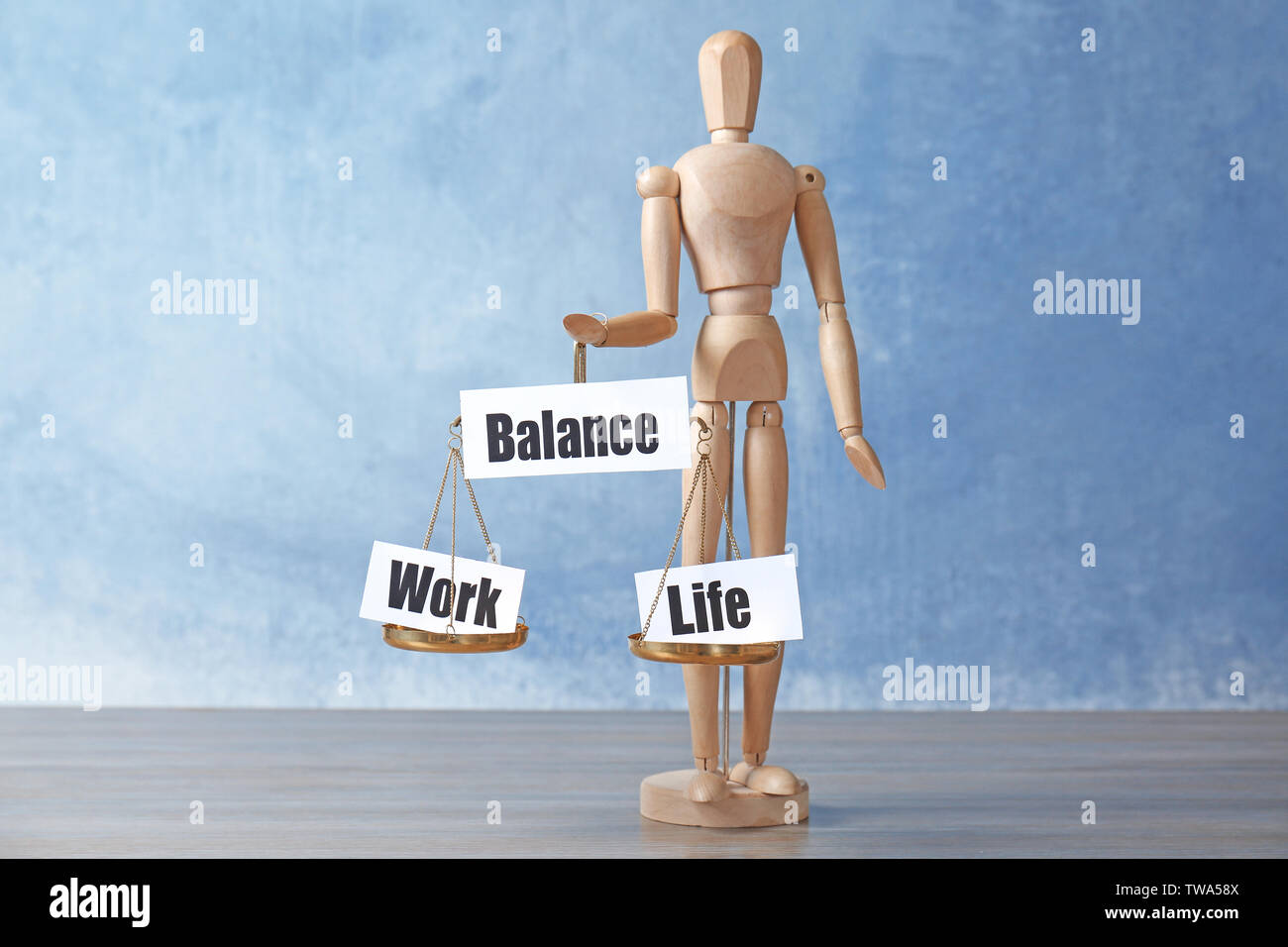Wooden figure holding scales with words WORK, LIFE and BALANCE on table ...