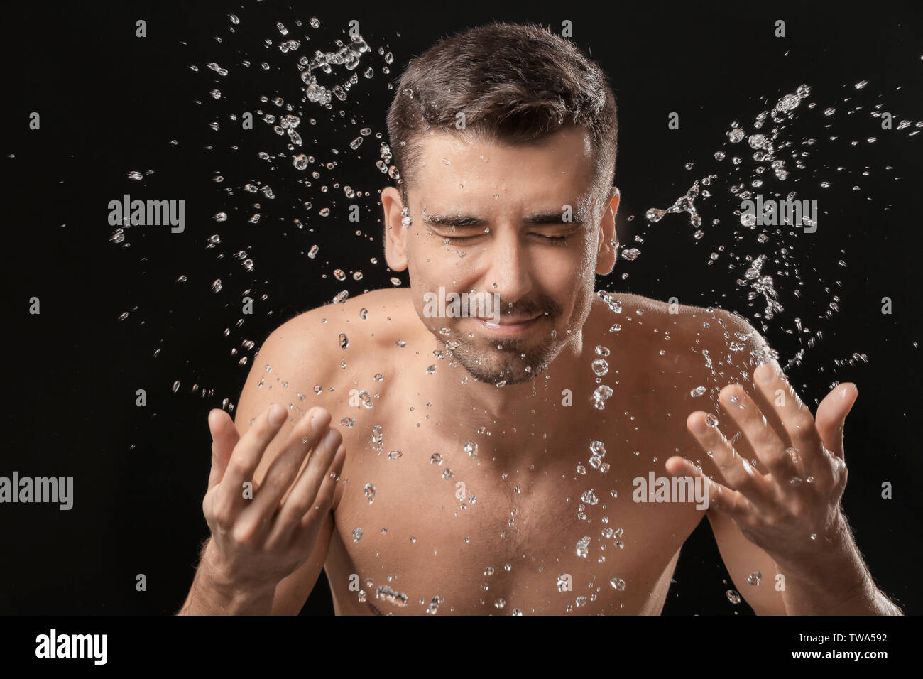 Man spraying water on his face after shaving on black background Stock ...