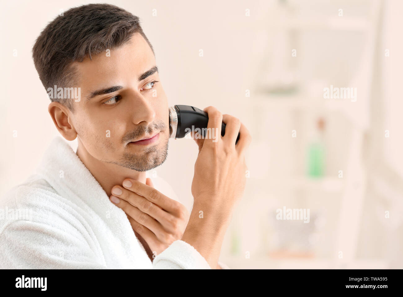 Handsome young man shaving in bathroom Stock Photo - Alamy