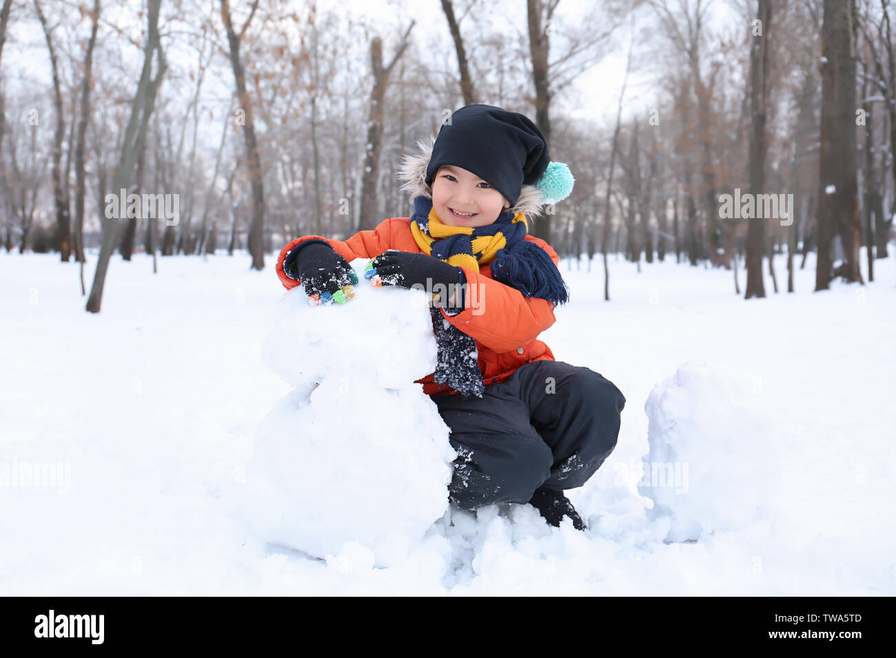 Cute boy making snowman in park on winter vacation Stock Photo - Alamy