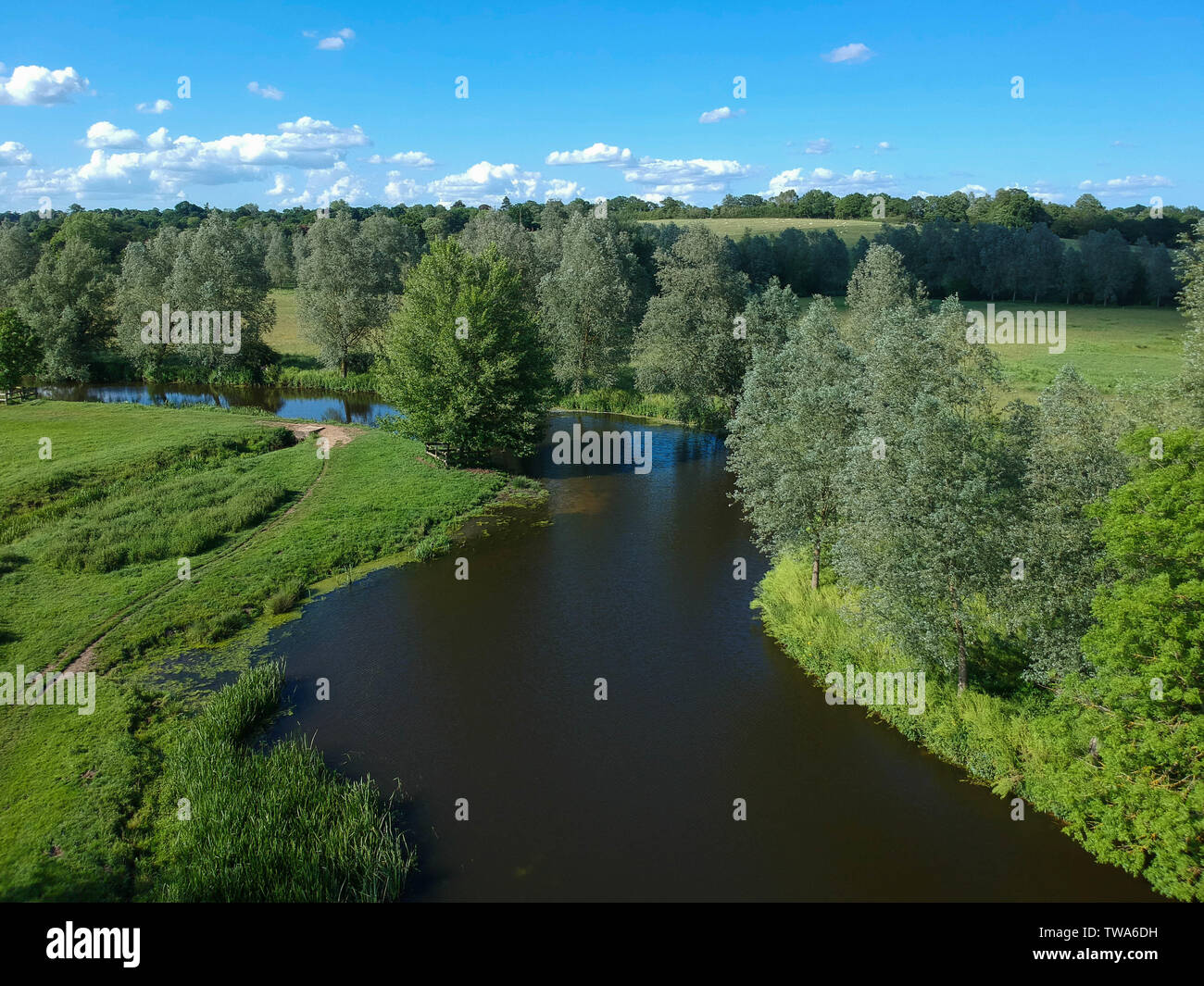 Arial view of a river winding through English countryside. Green fields ...