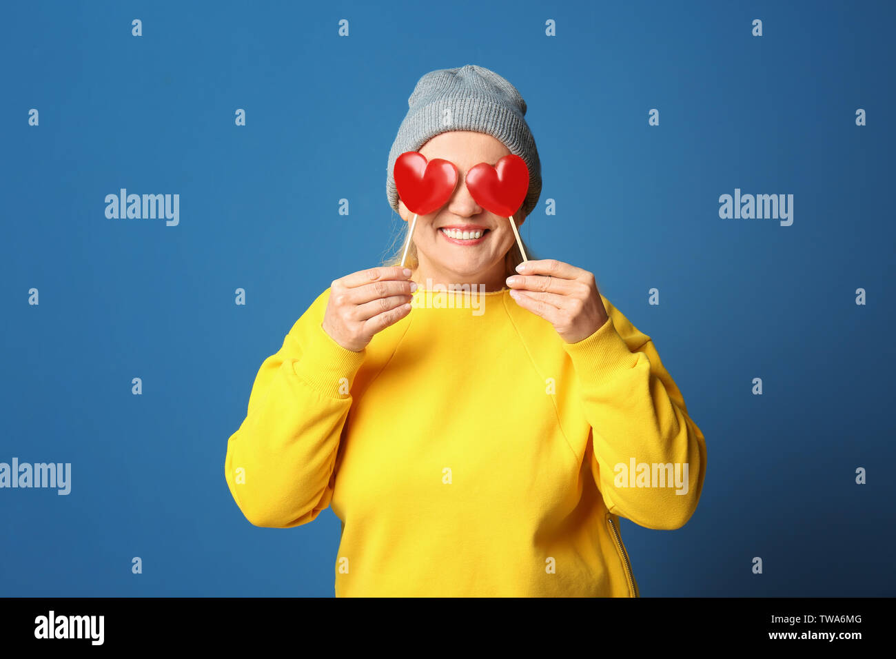 Portrait of stylish female pensioner with lollipops on color background ...