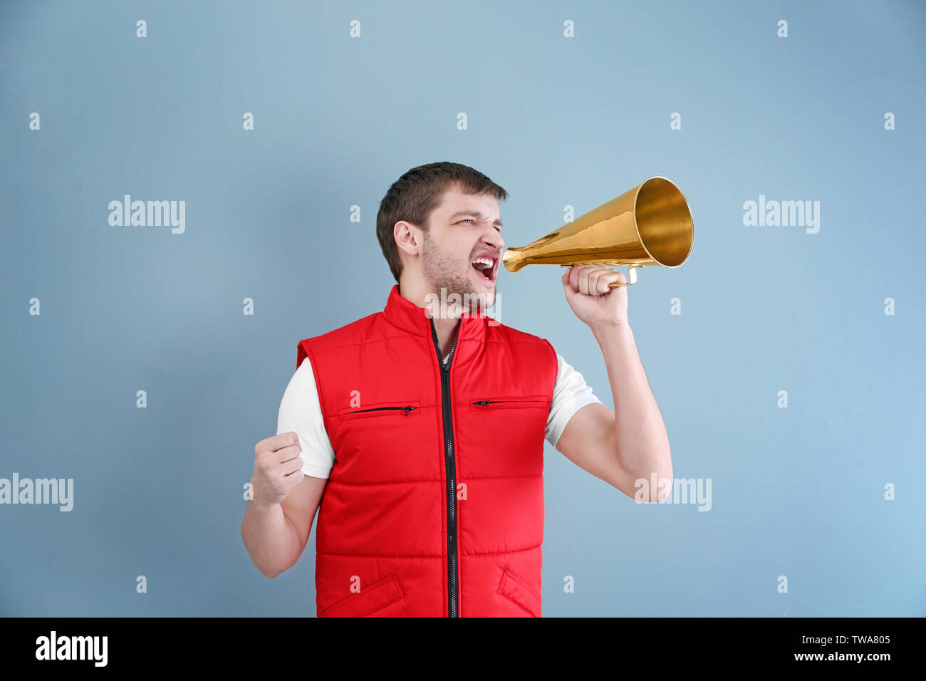 Angry man in red vest shouting into megaphone on color background Stock ...