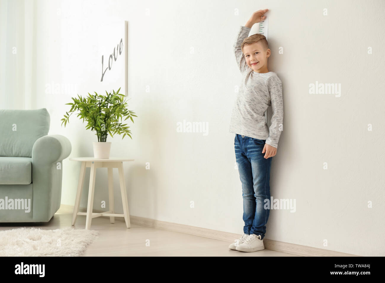 Cute little boy measuring height near wall at home Stock Photo - Alamy