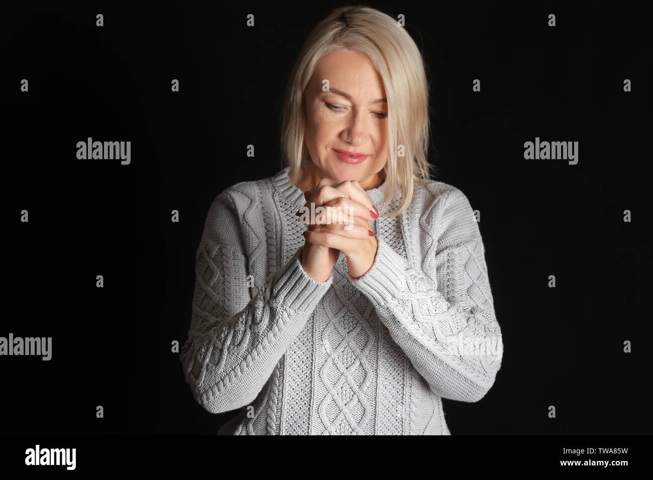 Religious mature woman praying on black background Stock Photo - Alamy