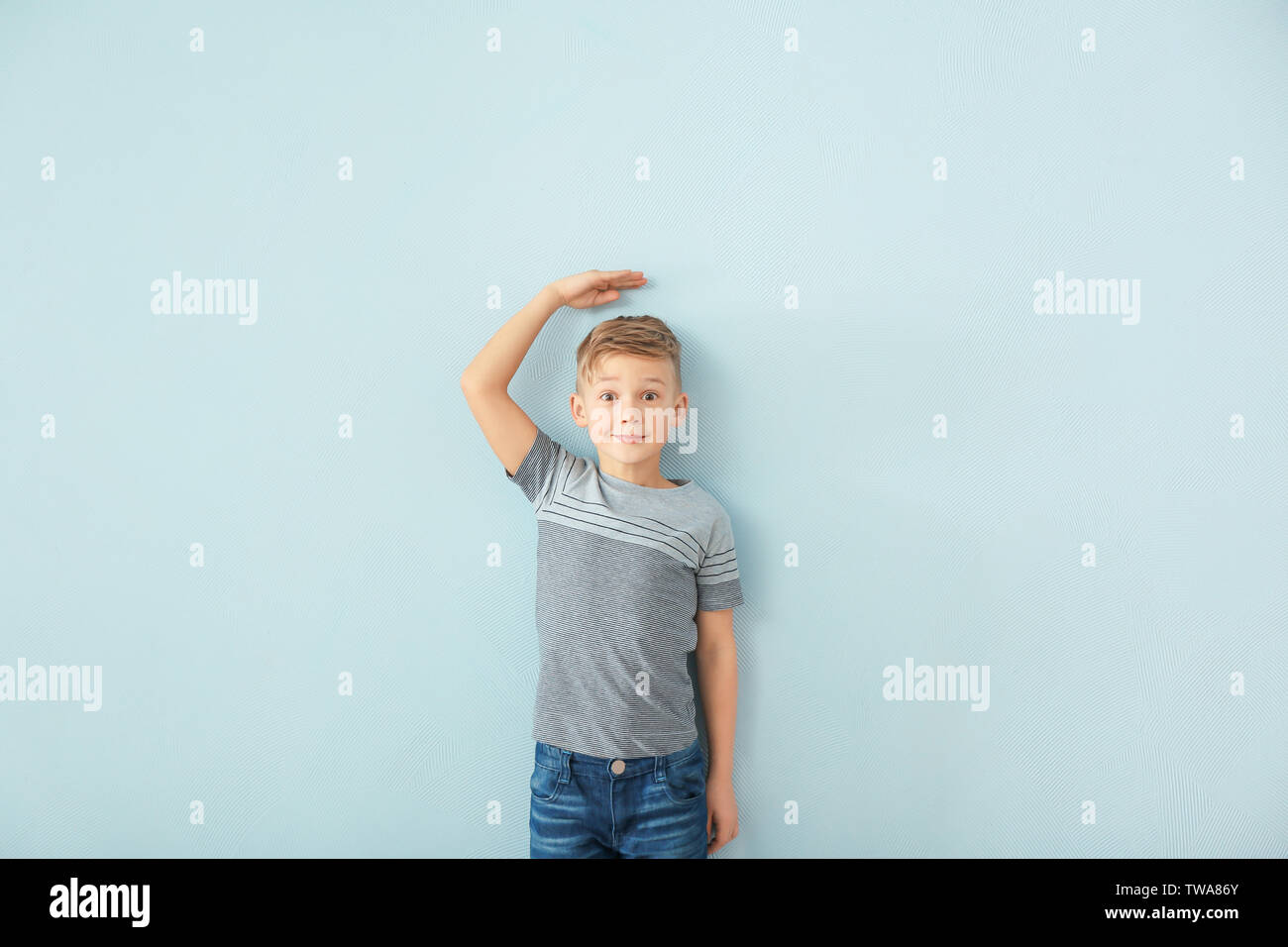 Cute little boy measuring height near color wall Stock Photo - Alamy