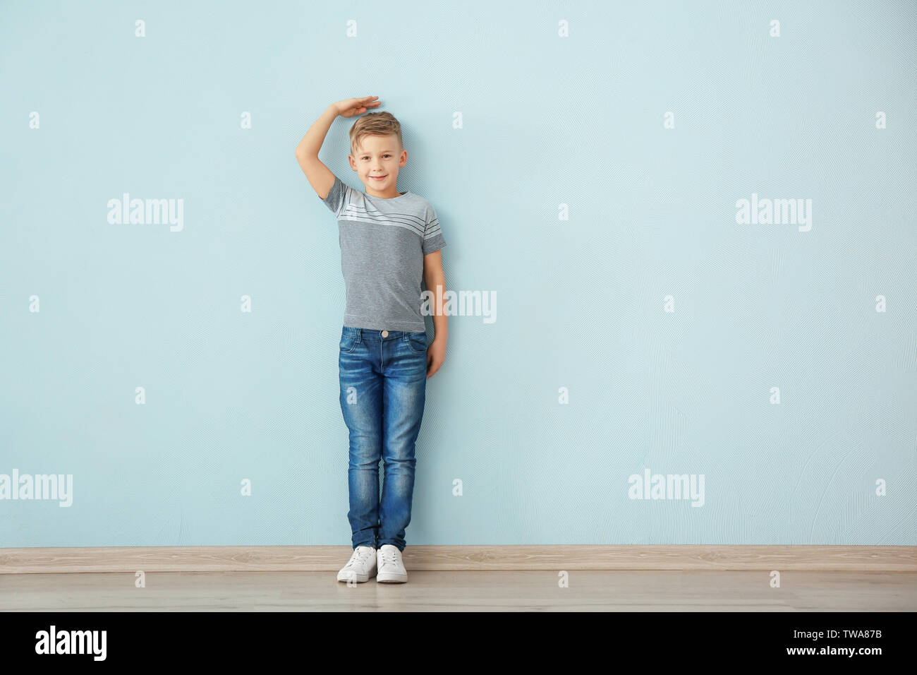 Cute little boy measuring height near color wall Stock Photo - Alamy