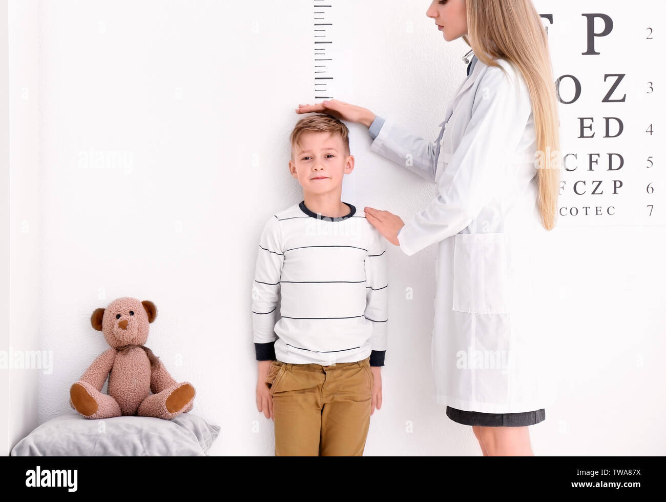 Young female doctor measuring height of little boy in hospital Stock ...