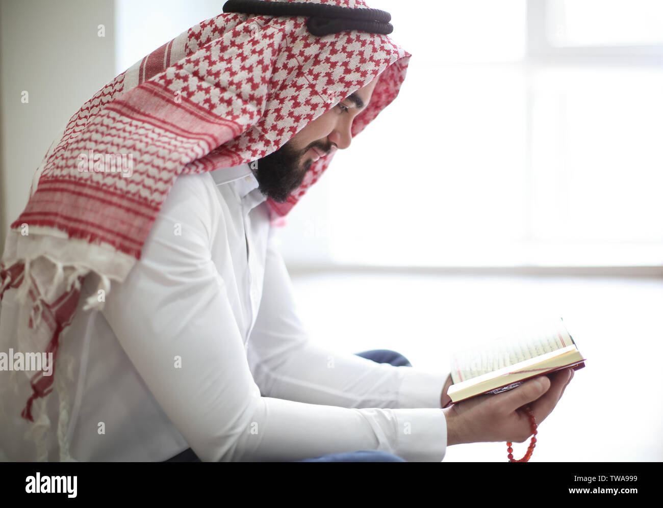 Young Muslim man reading Koran, indoors Stock Photo - Alamy