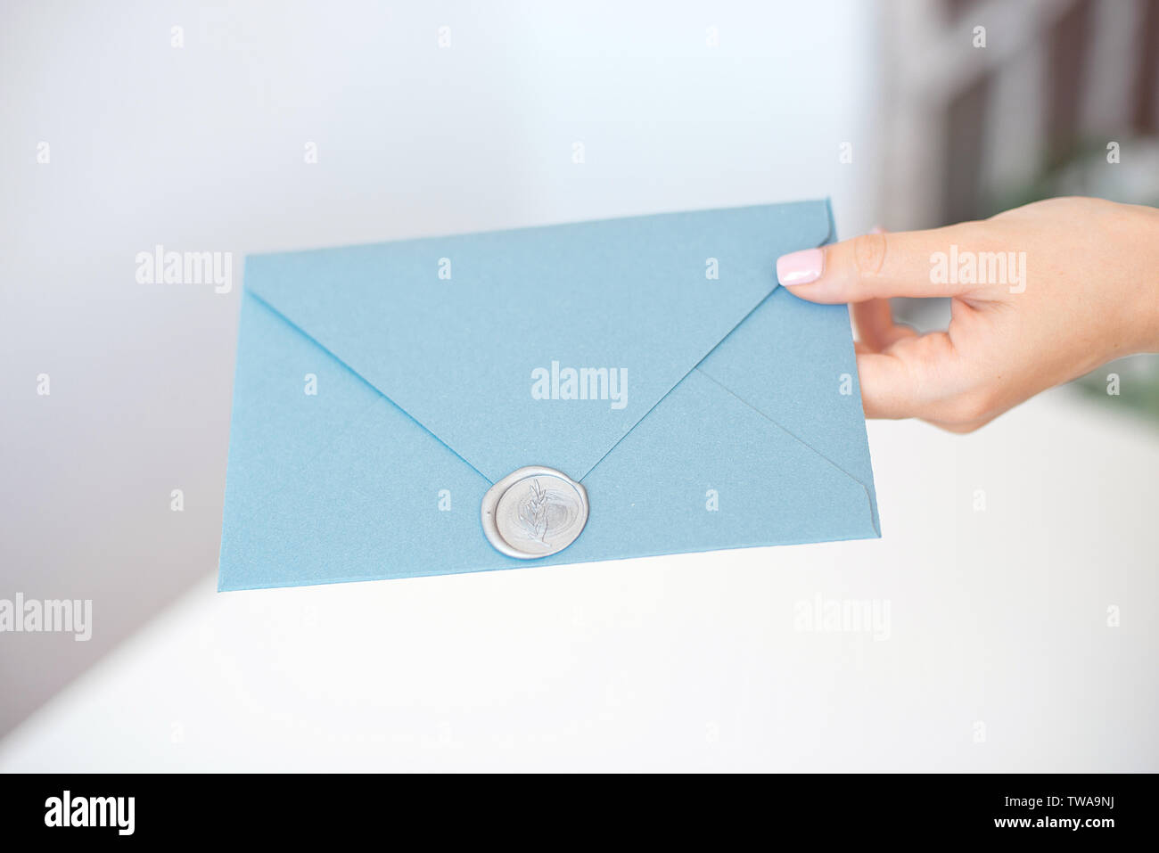Close-up woman with slim body holding in hands the invitation card blue ...
