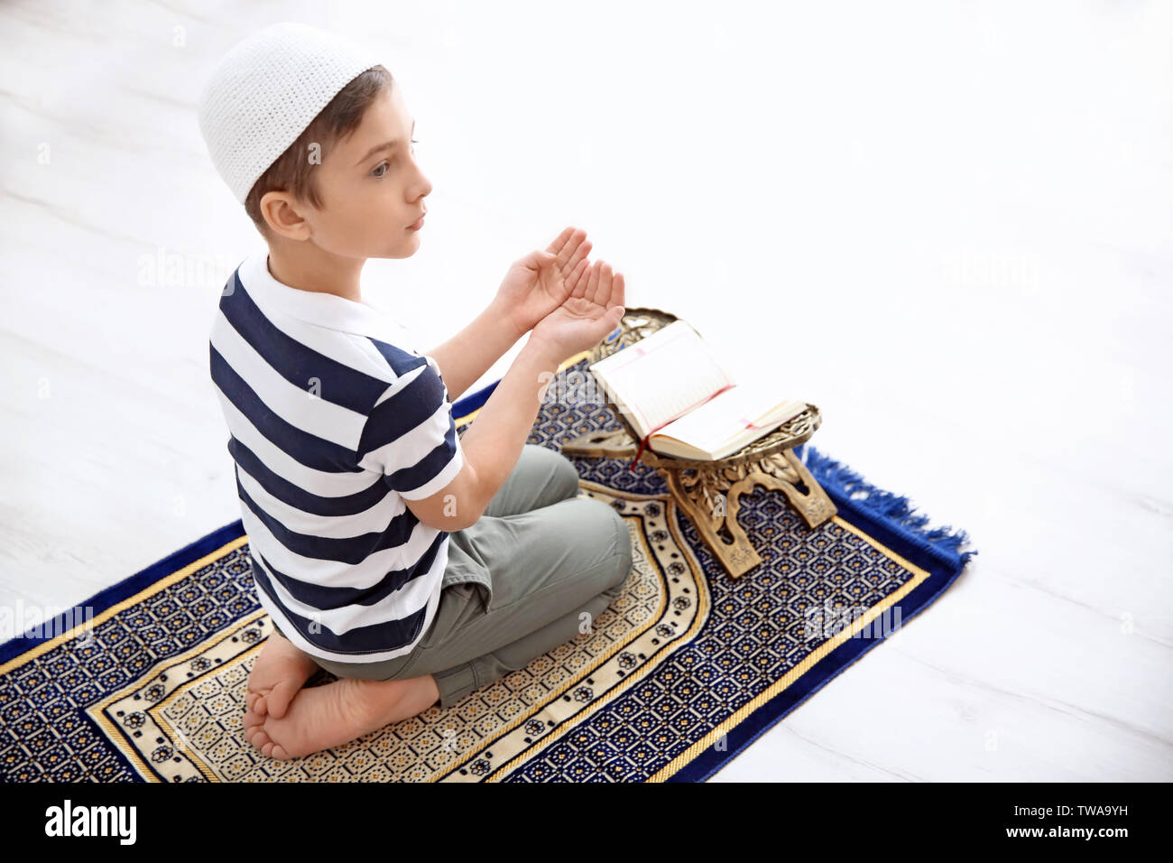 Muslim boy praying on rug at home Stock Photo - Alamy
