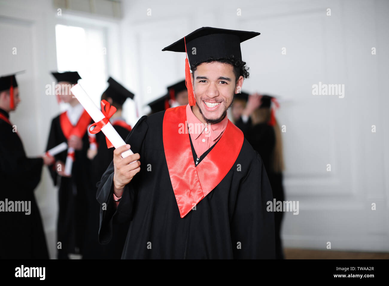Happy student in bachelor robe with diploma indoors. Graduation day ...