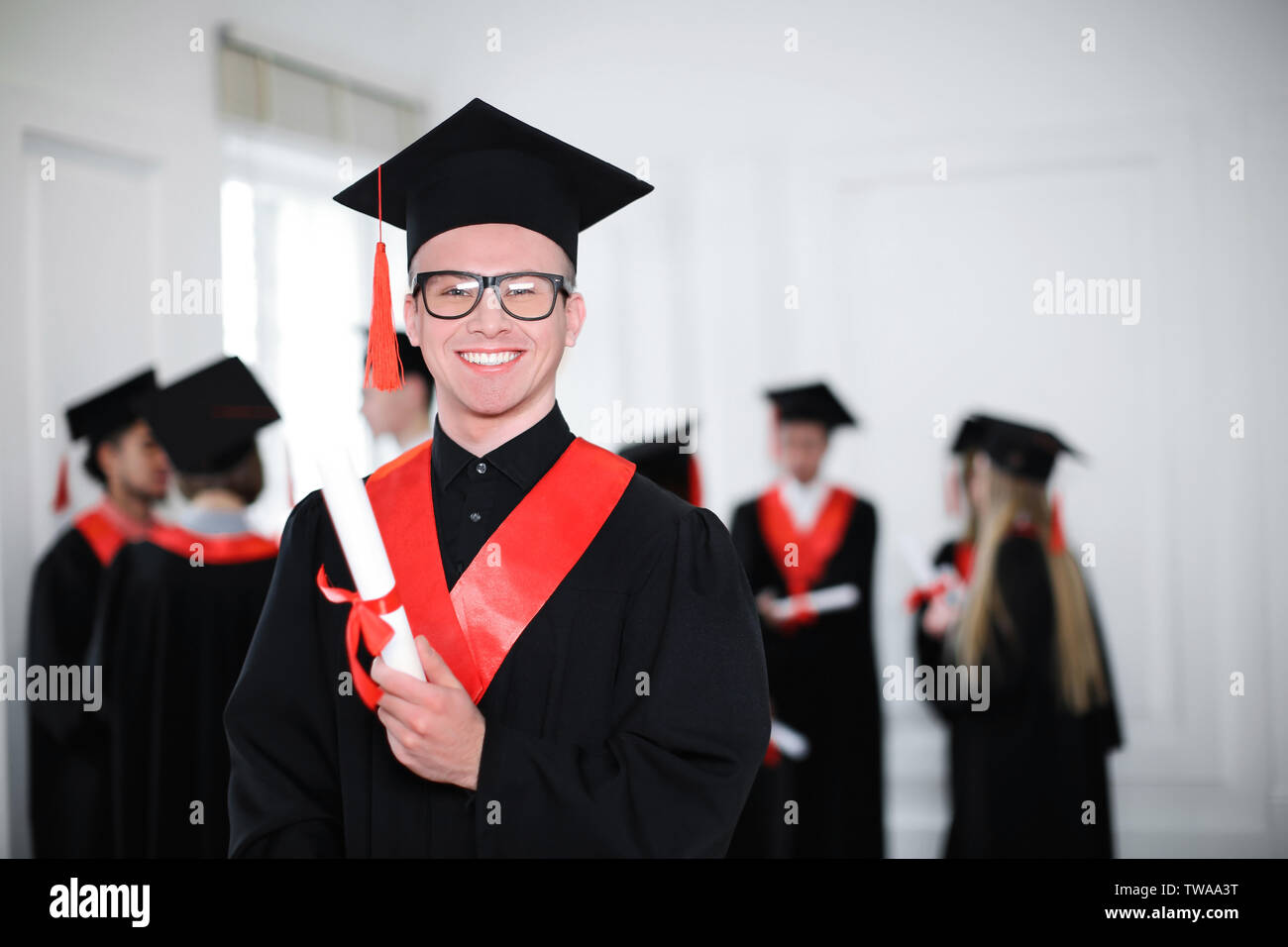 Happy student in bachelor robe with diploma indoors. Graduation day ...