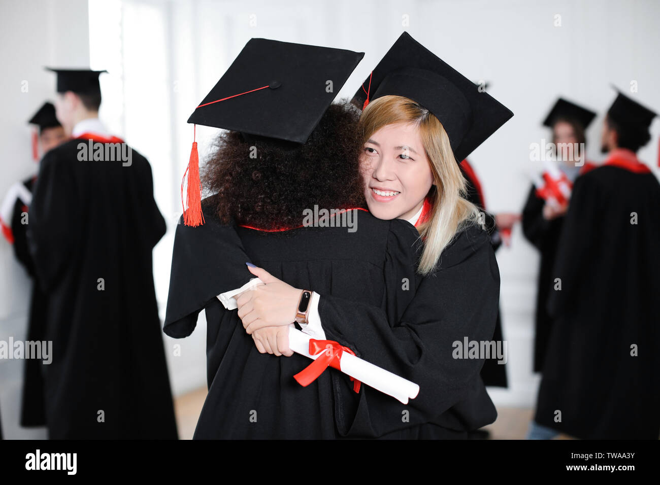 Happy students in bachelor robes hugging indoors, Graduation day Stock ...