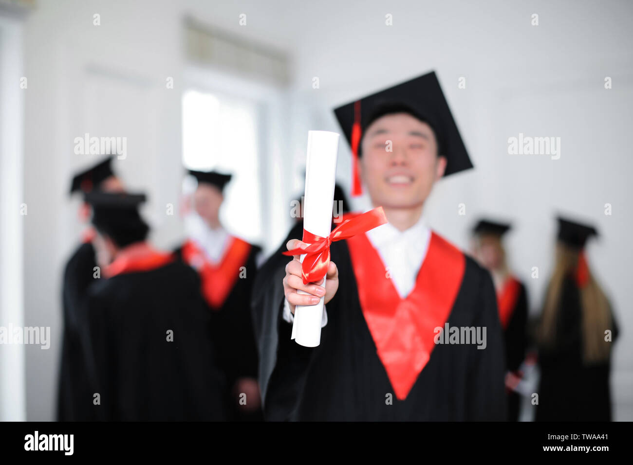 Happy student in bachelor robe with diploma indoors. Graduation day ...