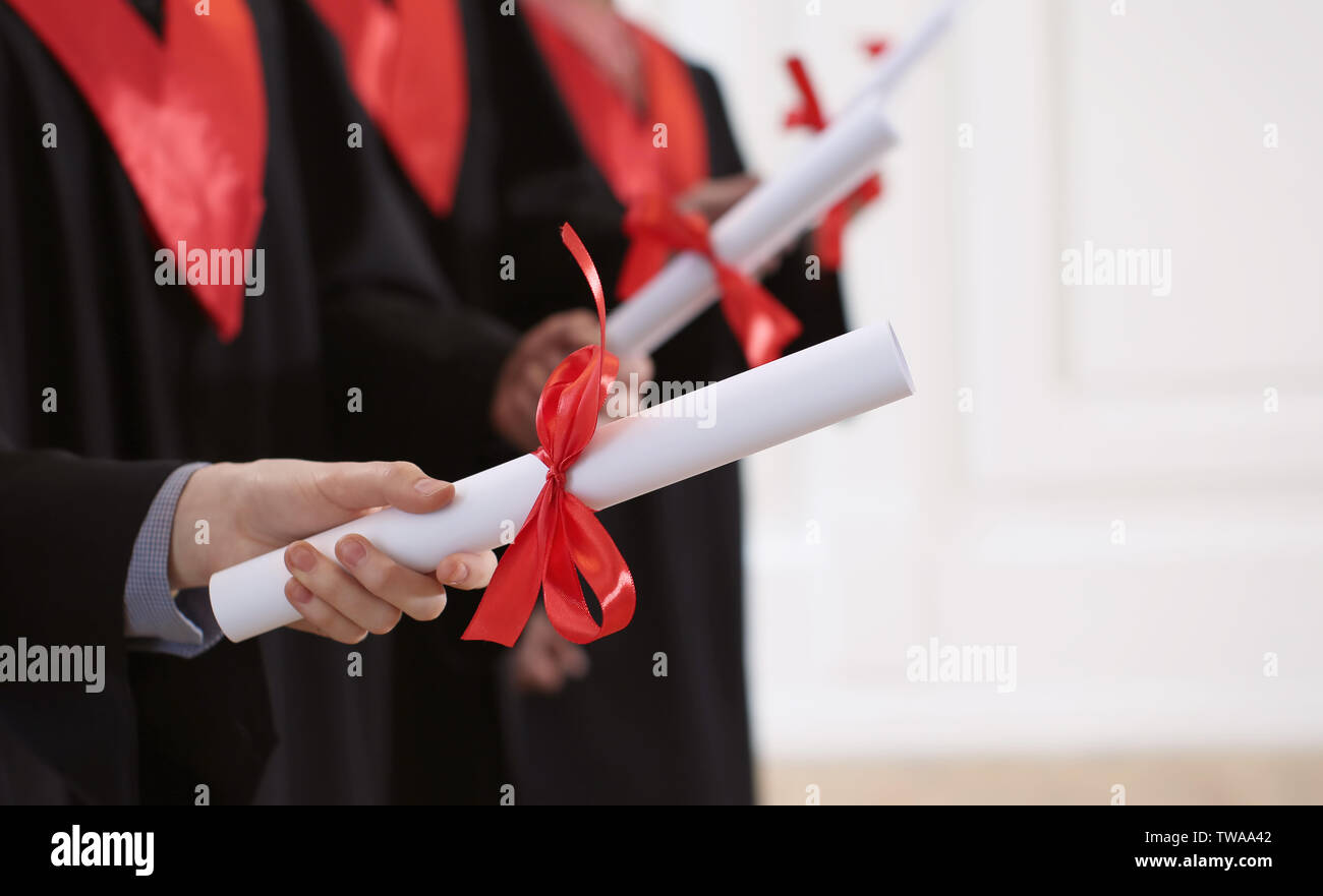 Students in bachelor robes with diplomas indoors. Graduation day Stock ...