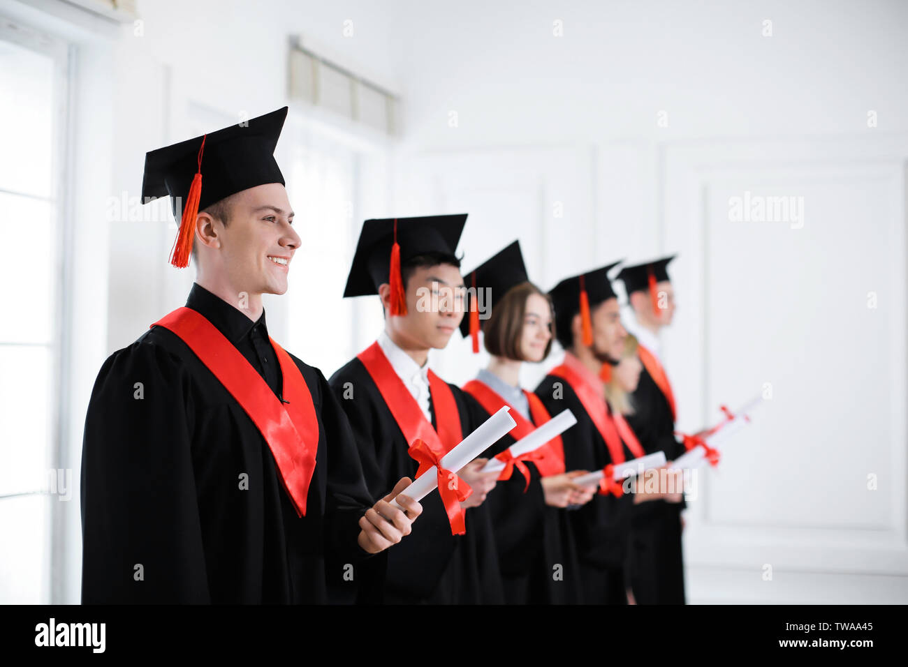 Students in bachelor robes with diplomas indoors. Graduation day Stock ...