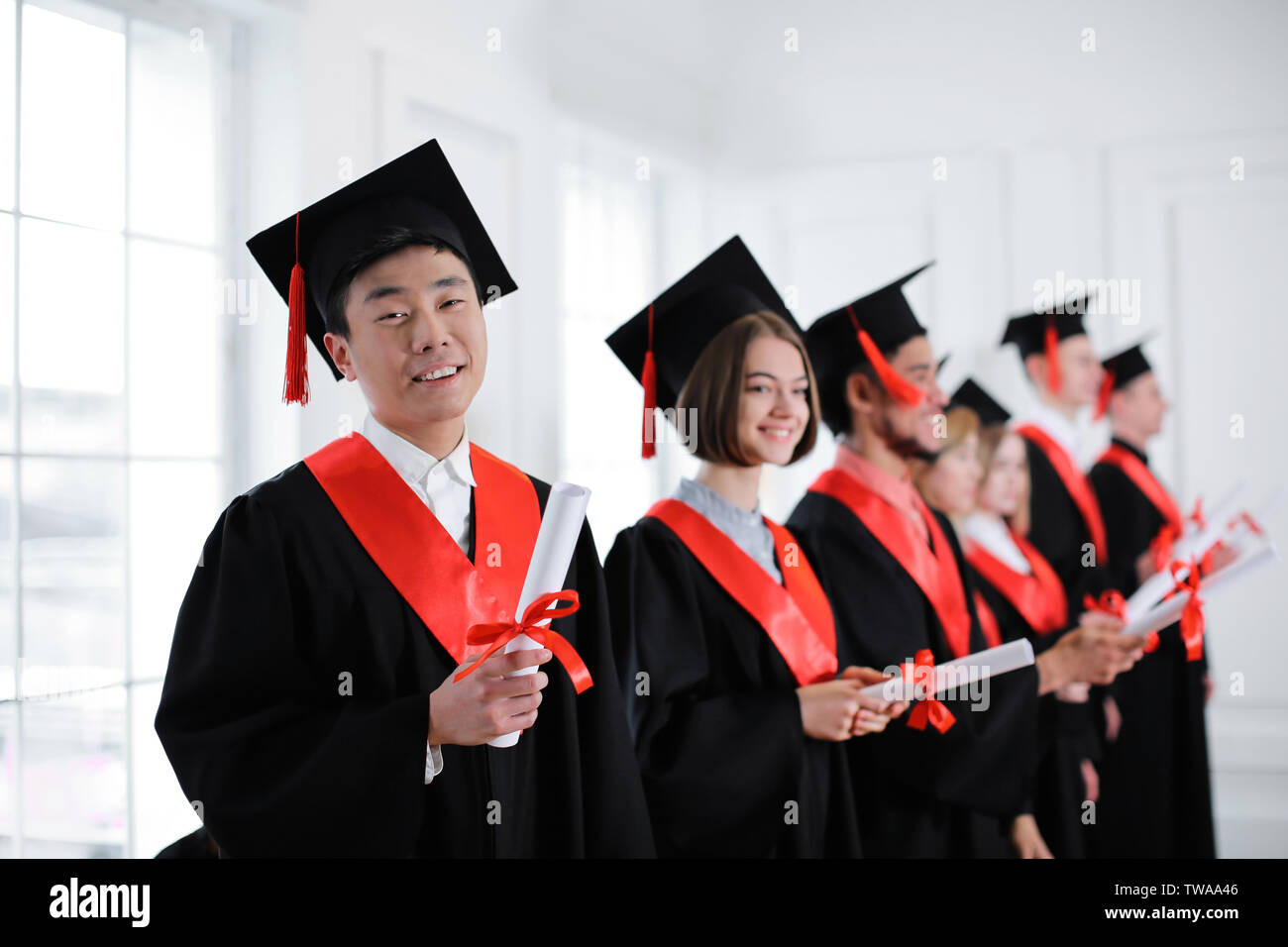 Students in bachelor robes with diplomas indoors. Graduation day Stock ...