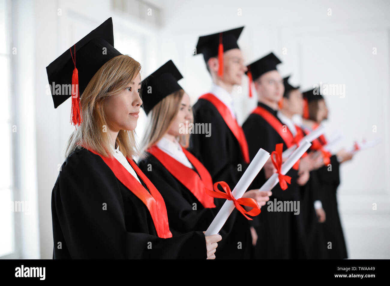 Students in bachelor robes with diplomas indoors. Graduation day Stock ...