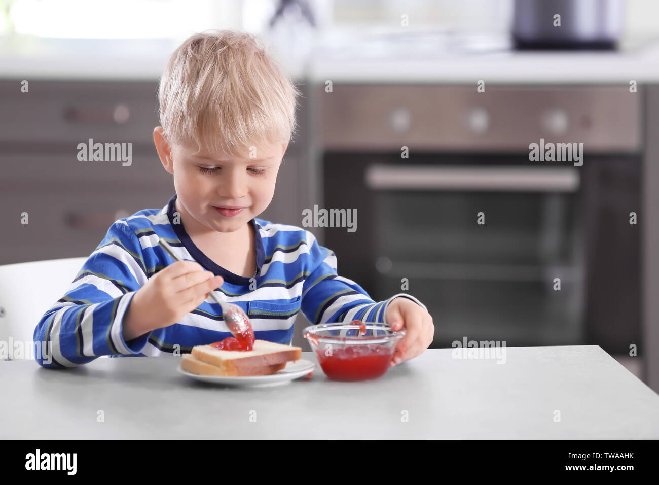 Cute little boy spreading jam on toast at home Stock Photo - Alamy