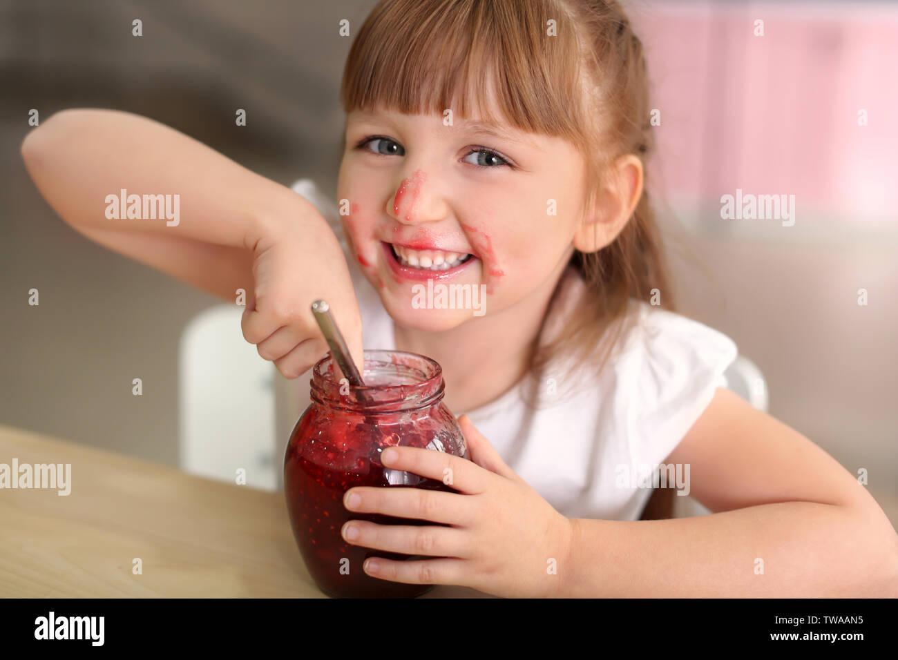 Cute little girl eating jam at home Stock Photo - Alamy