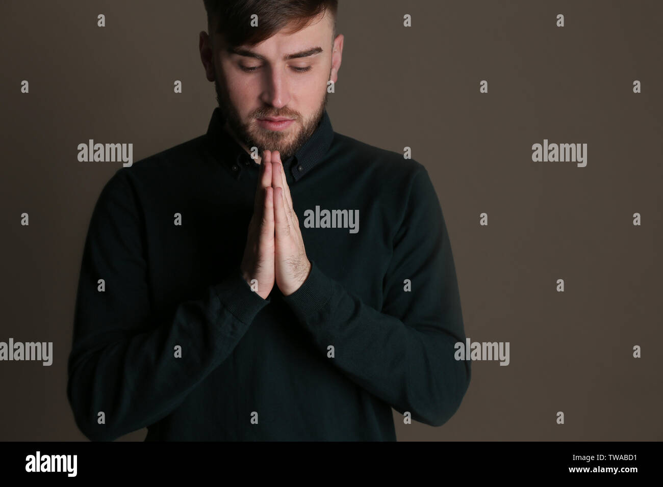 Religious young man praying on dark background Stock Photo - Alamy