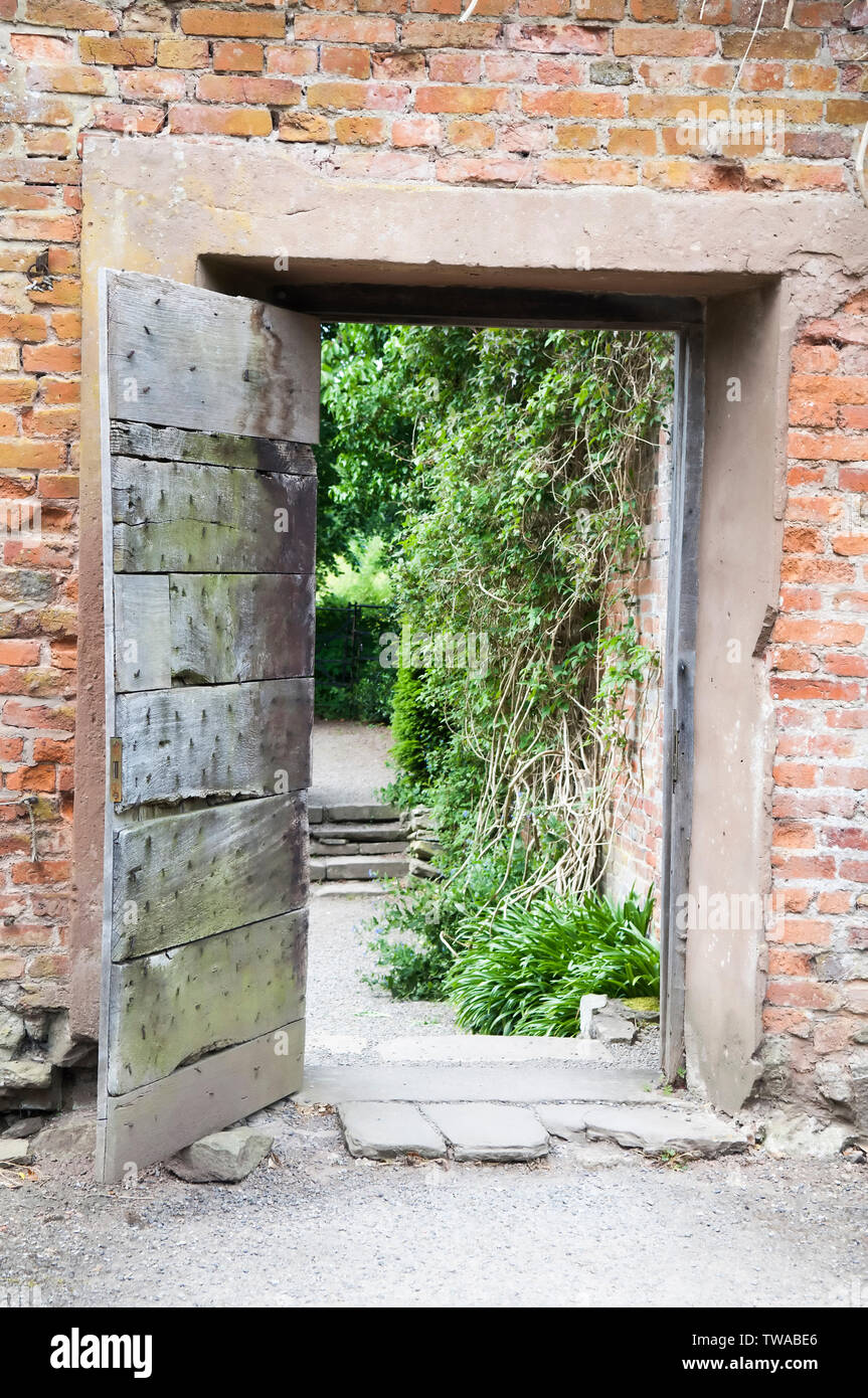 An open wooden garden door in a rustic wall Stock Photo - Alamy
