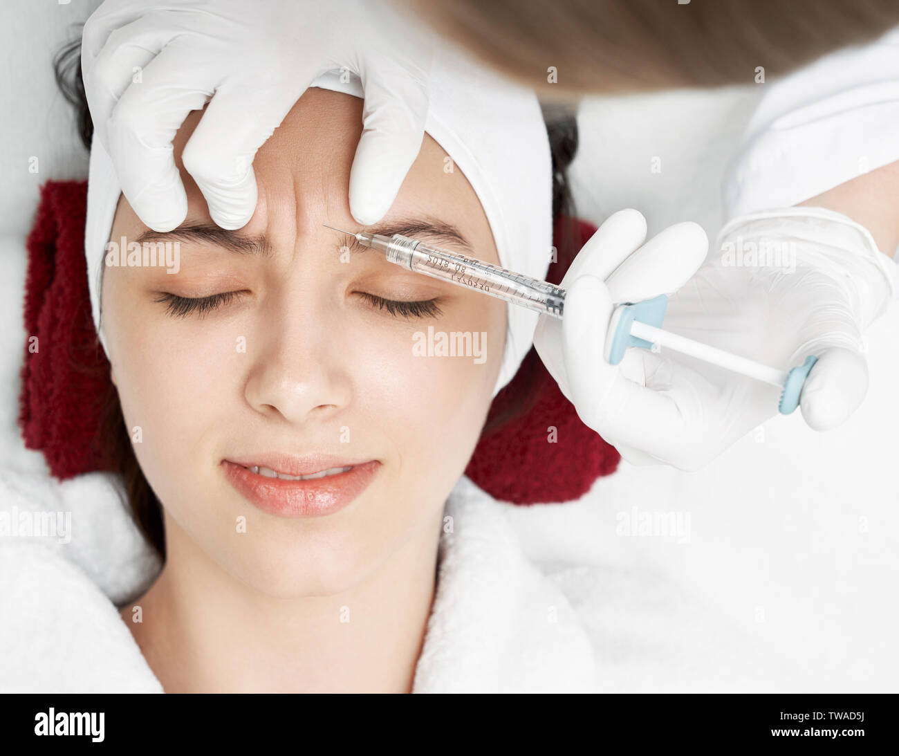 View from above of pretty woman lying while female cosmetologist doing ...