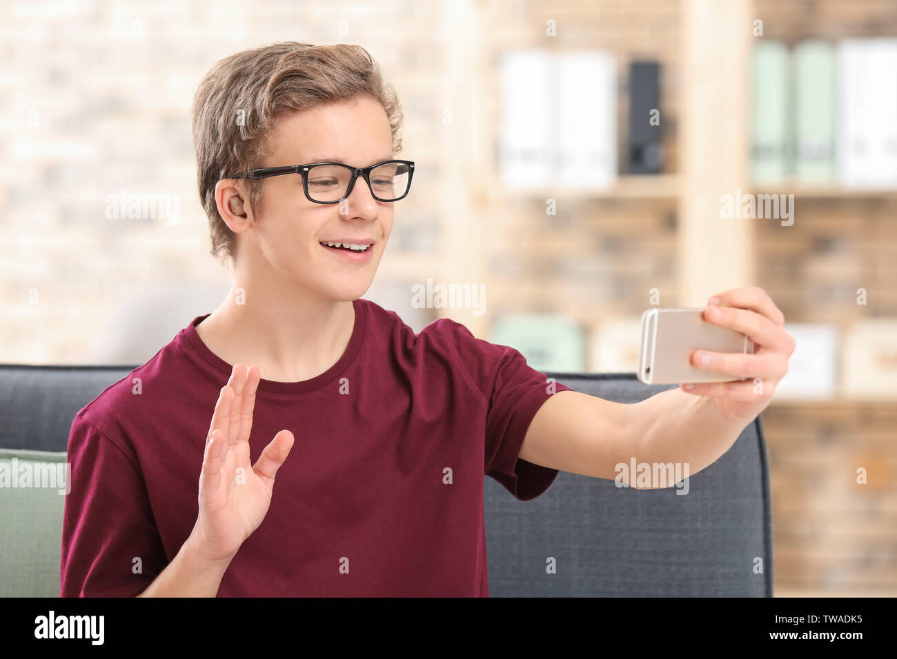 Teenage boy with hearing aid using smartphone indoors Stock Photo - Alamy